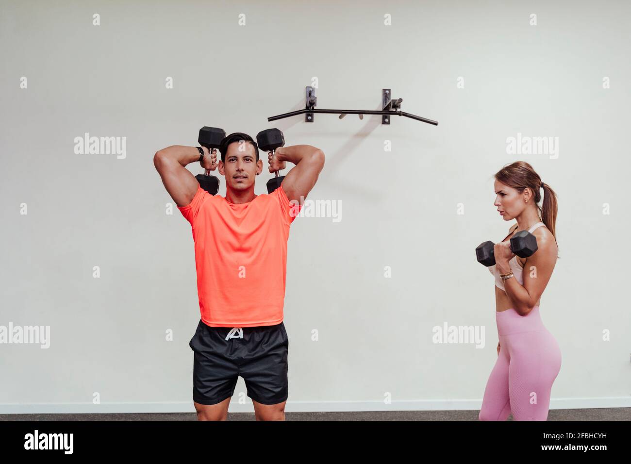 Male and female athletes exercising with dumbbell in gym Stock Photo ...