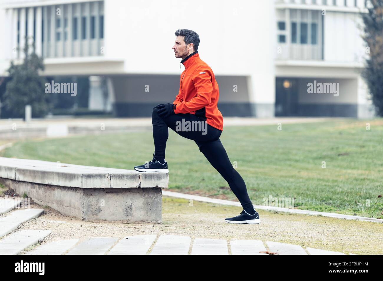 Determined male athlete doing stretching exercise at park Stock Photo ...