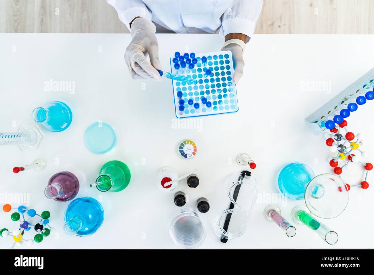 Female researcher removing test tube from microplate on table in ...