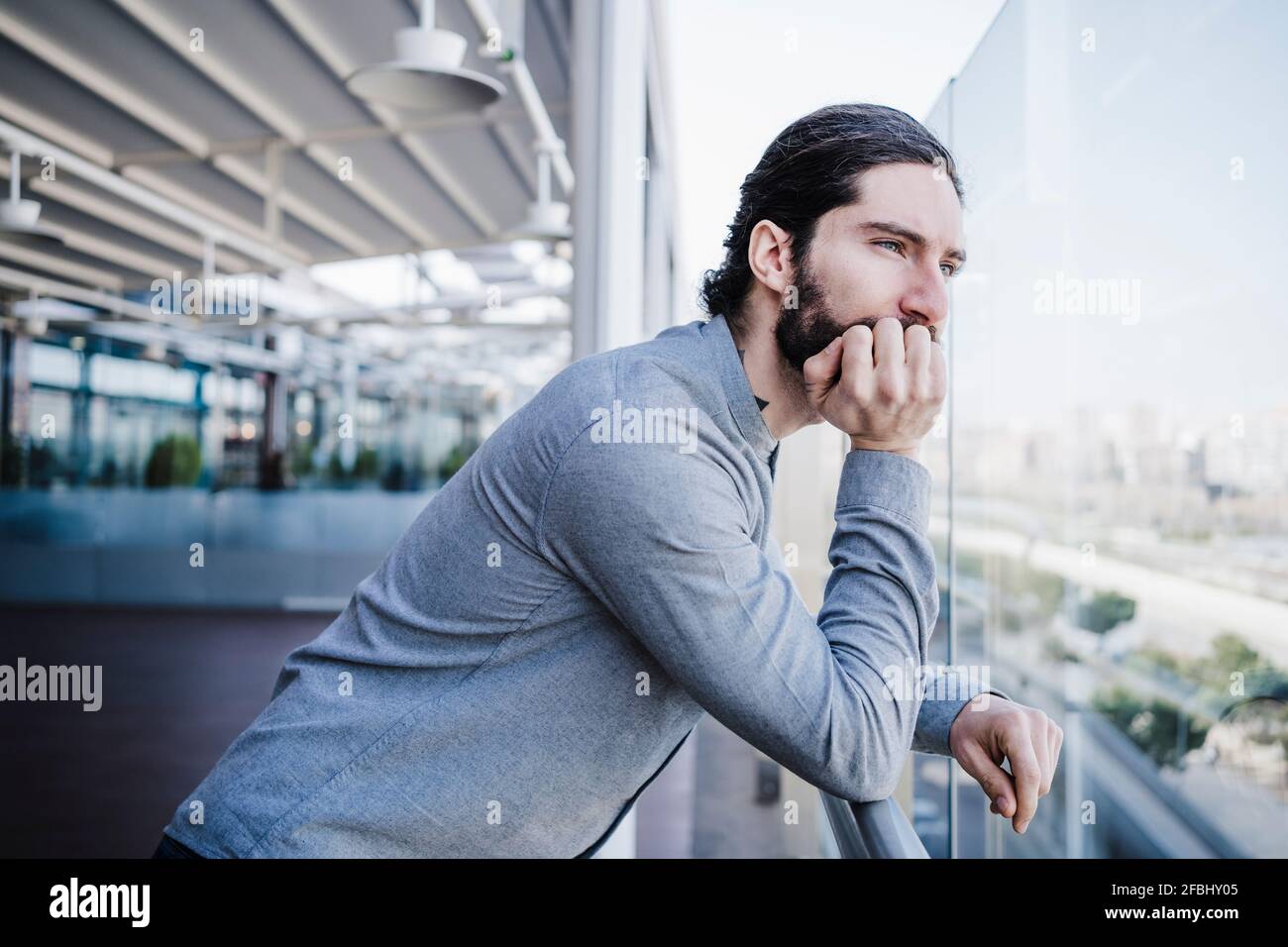 Contemplative businessman looking through window while standing on ...