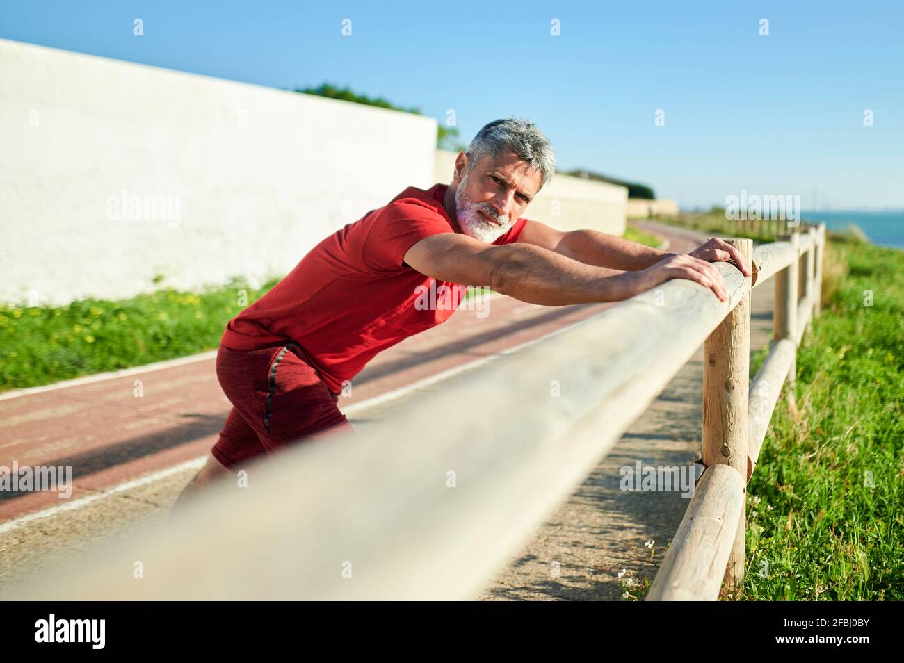 Handsome man stretching by railing Stock Photo - Alamy