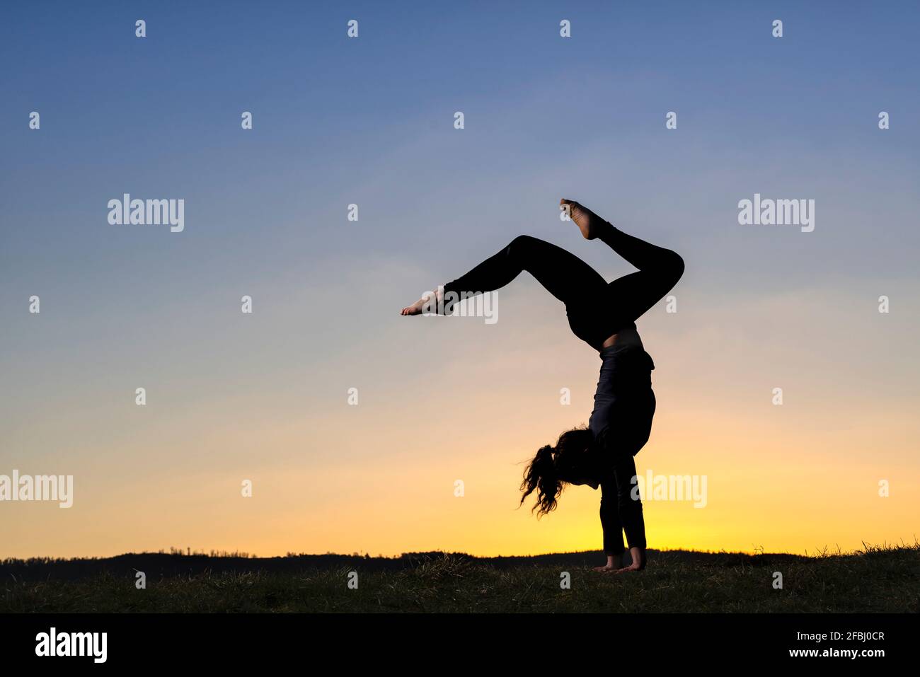 Young woman in silhouette doing handstand during sunset Stock Photo - Alamy