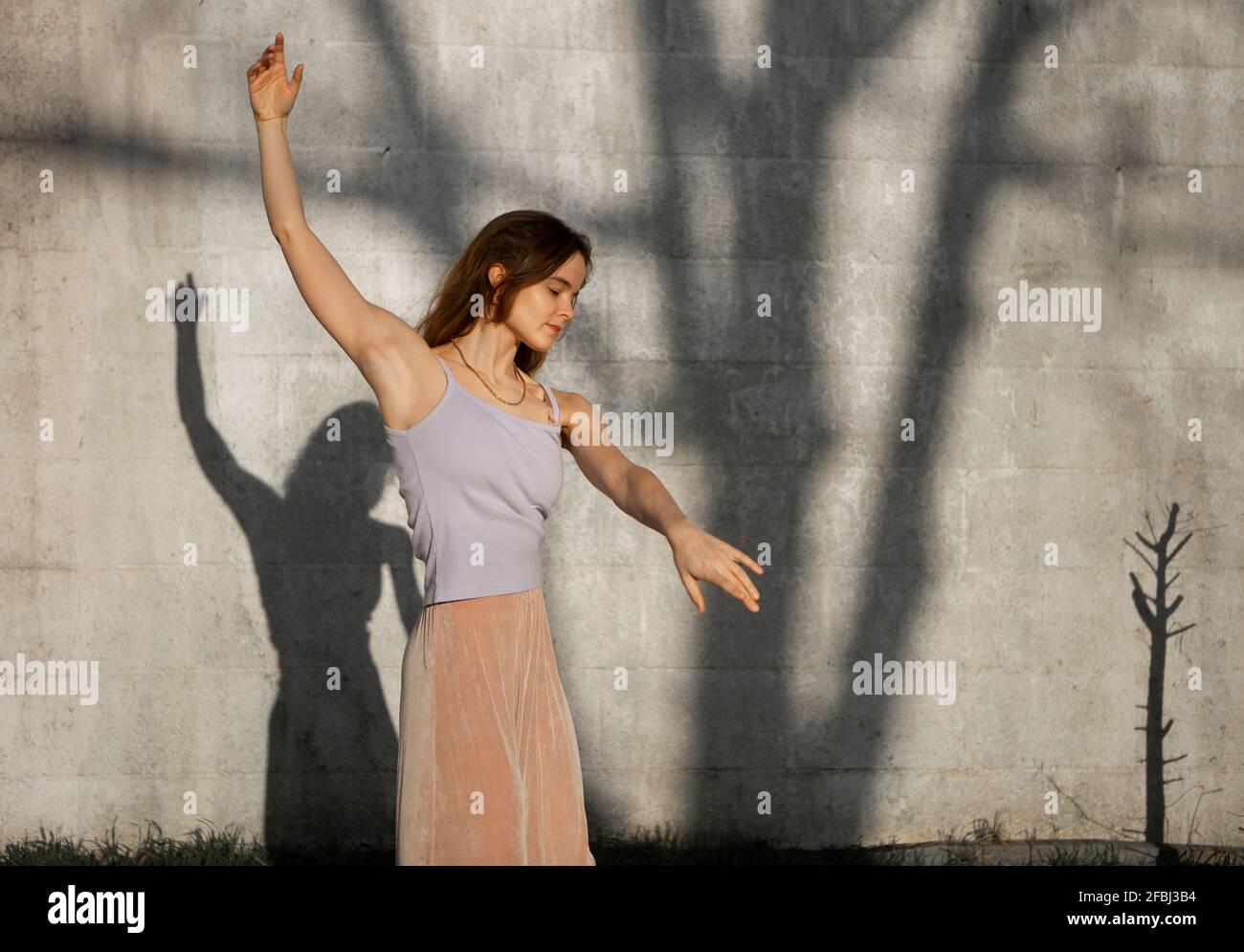 Woman with arms raised dancing against wall Stock Photo - Alamy