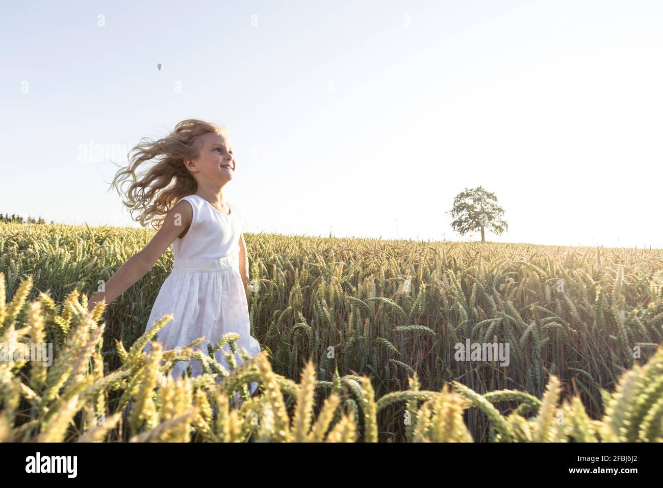 Smiling blond girl looking up while running on field Stock Photo - Alamy