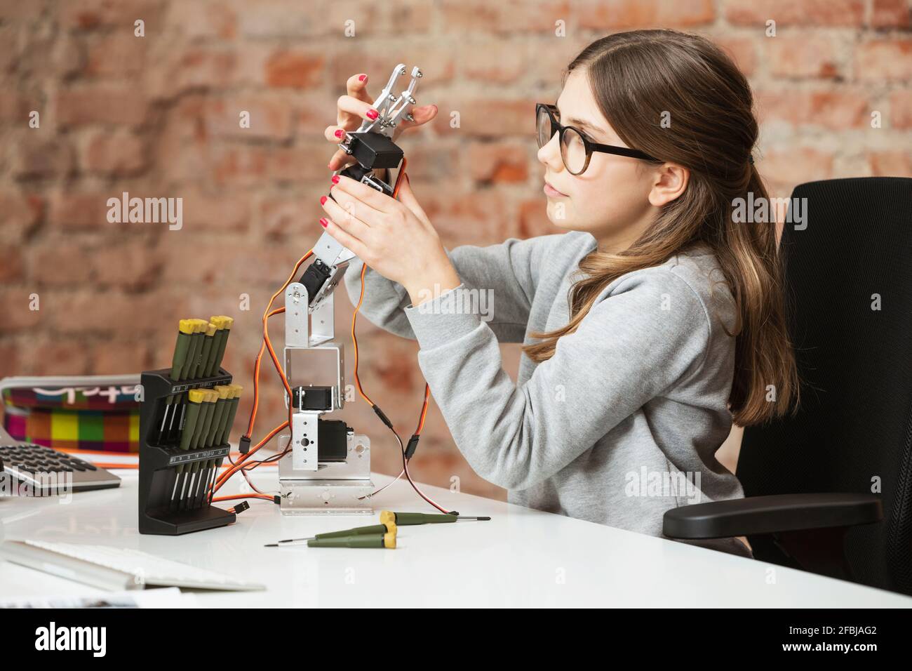 Girl building robotic arm while sitting at table Stock Photo - Alamy