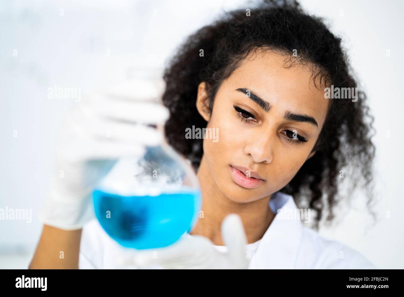 Female researcher holding flask with liquid in laboratory Stock Photo ...