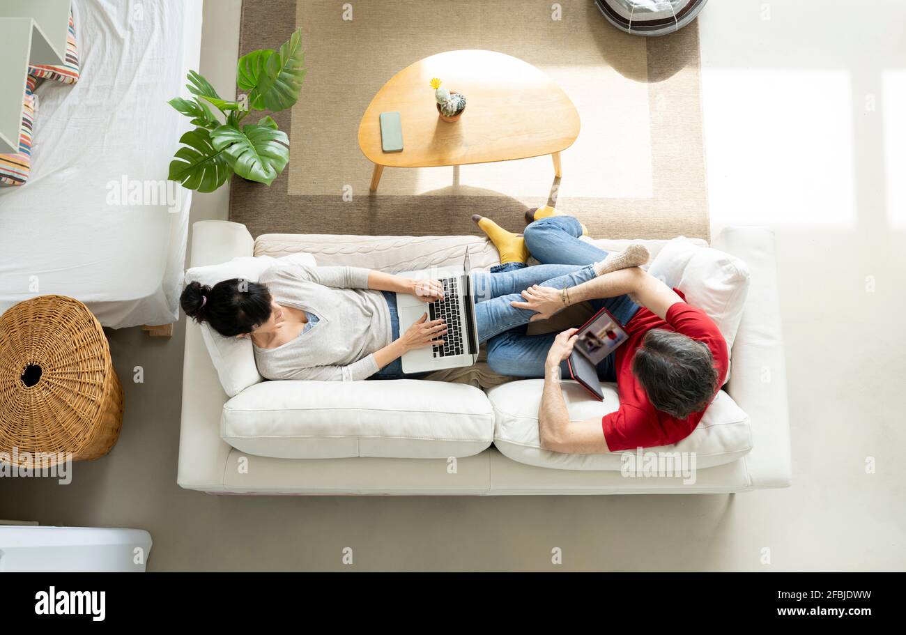 Couple relaxing on sofa in living room at home Stock Photo - Alamy