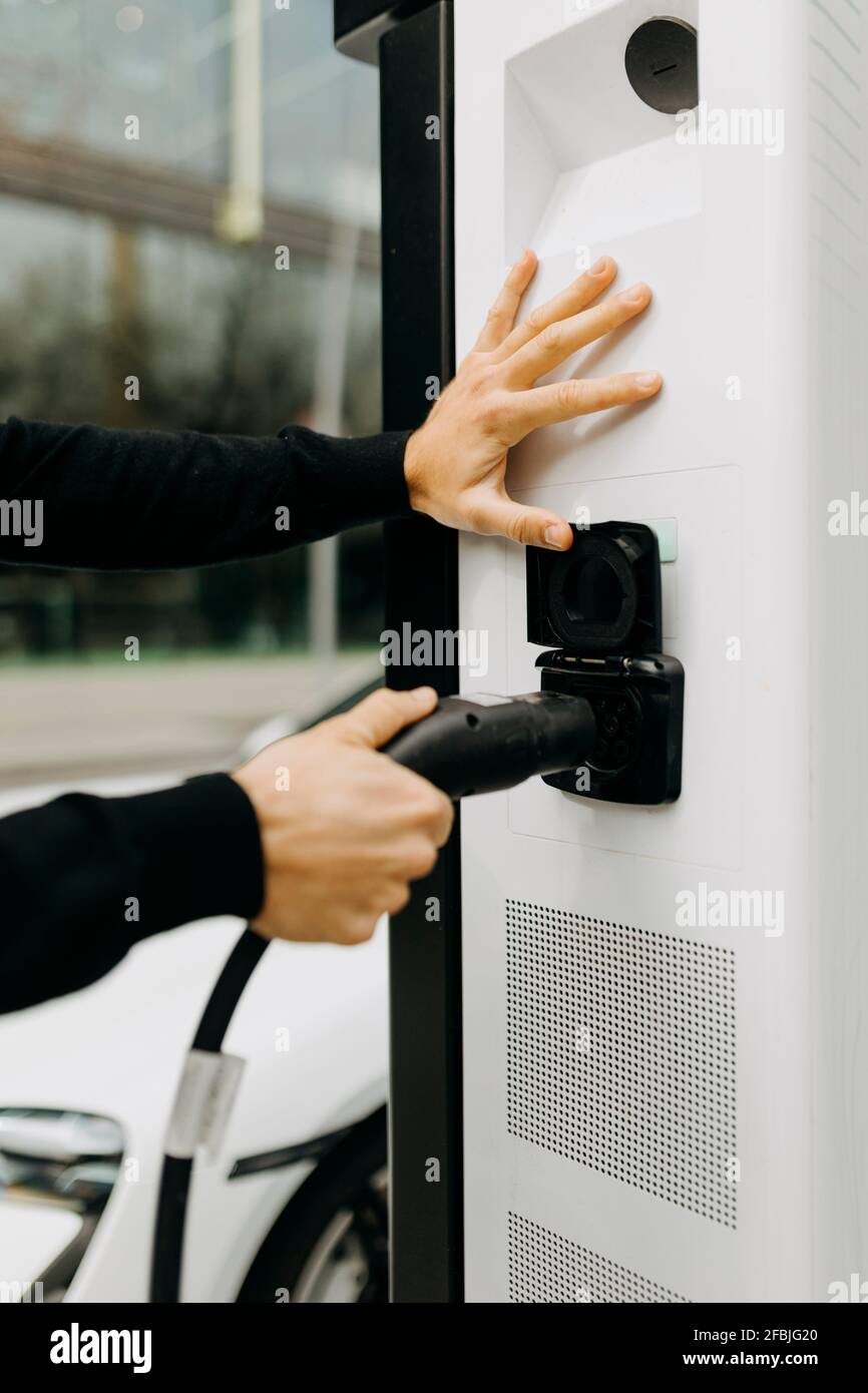 Man holding electric cord at charging station Stock Photo - Alamy