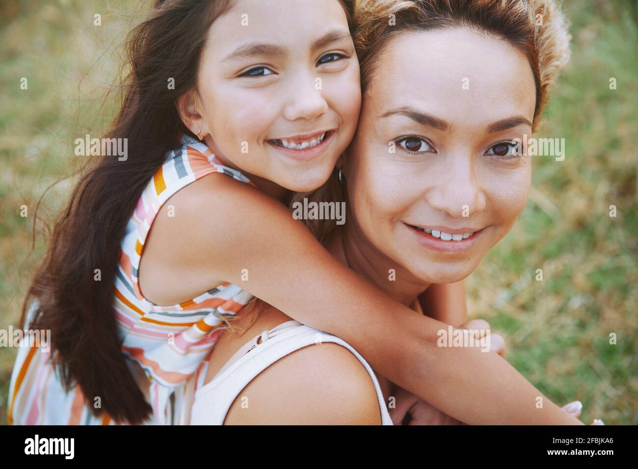 Smiling mother giving piggyback ride to daughter Stock Photo - Alamy