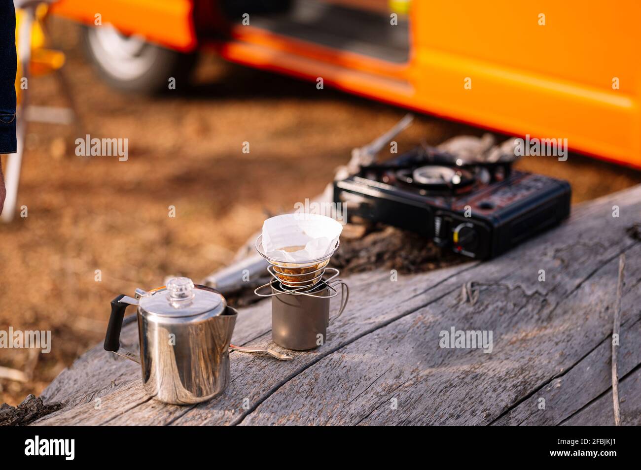 Kettle with coffee mug and camping stove on wooden log Stock Photo - Alamy