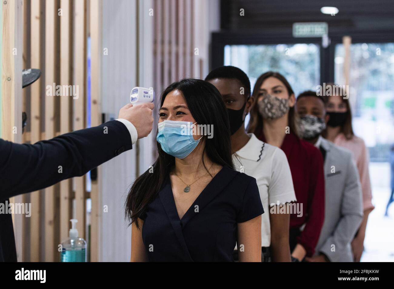 Employees with face mask going through temperature checkpoint at office ...
