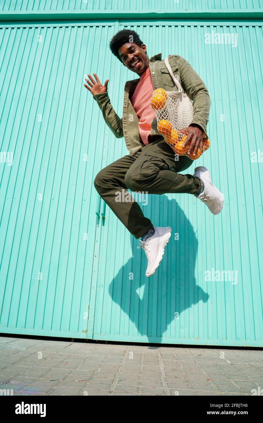 Cheerful man dancing in front of turquoise wall during sunny day Stock ...