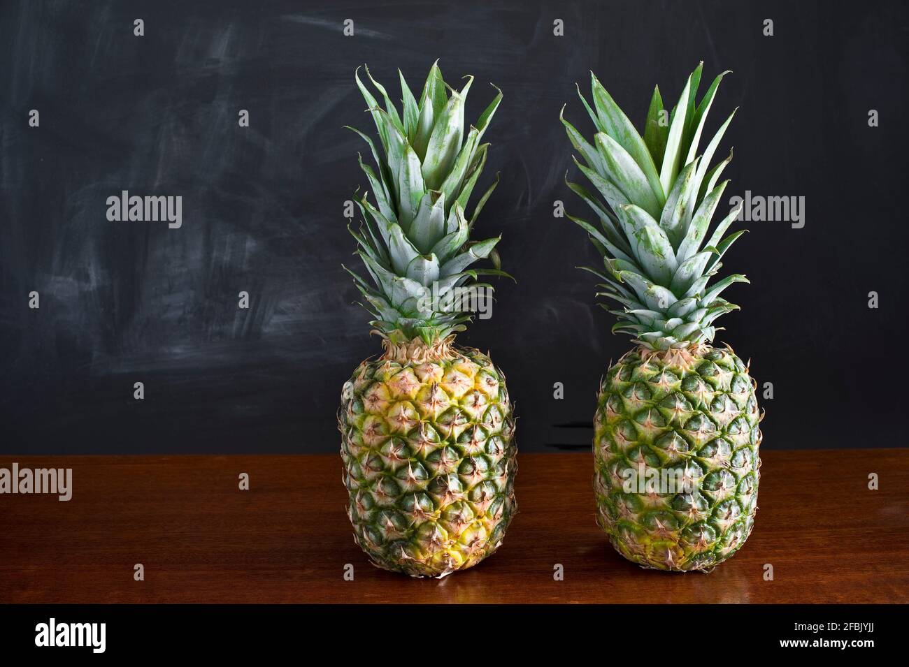 Still life with two pineapples in front of dark wall Stock Photo - Alamy