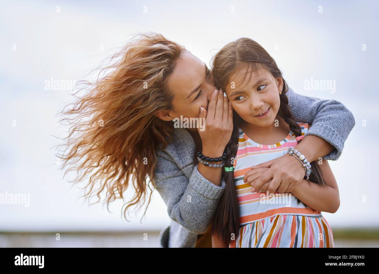 Mother whispering secret in daughter's ear Stock Photo - Alamy
