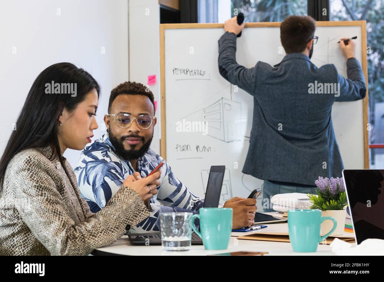 Business people using mobile phones with colleague working in ...