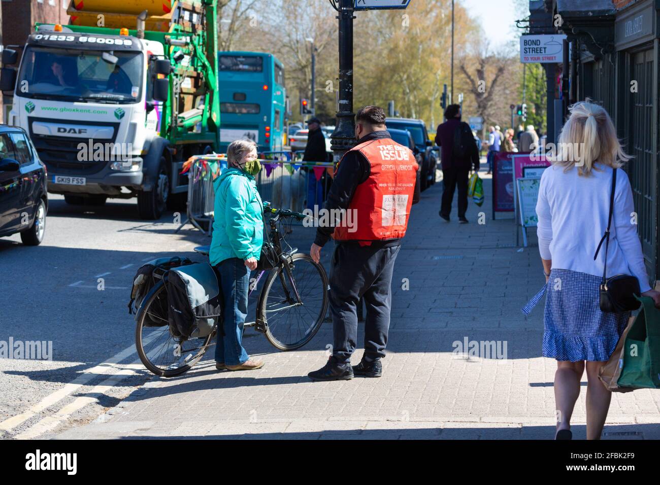 The big issue seller talking to a woman on a bike in the high street ...