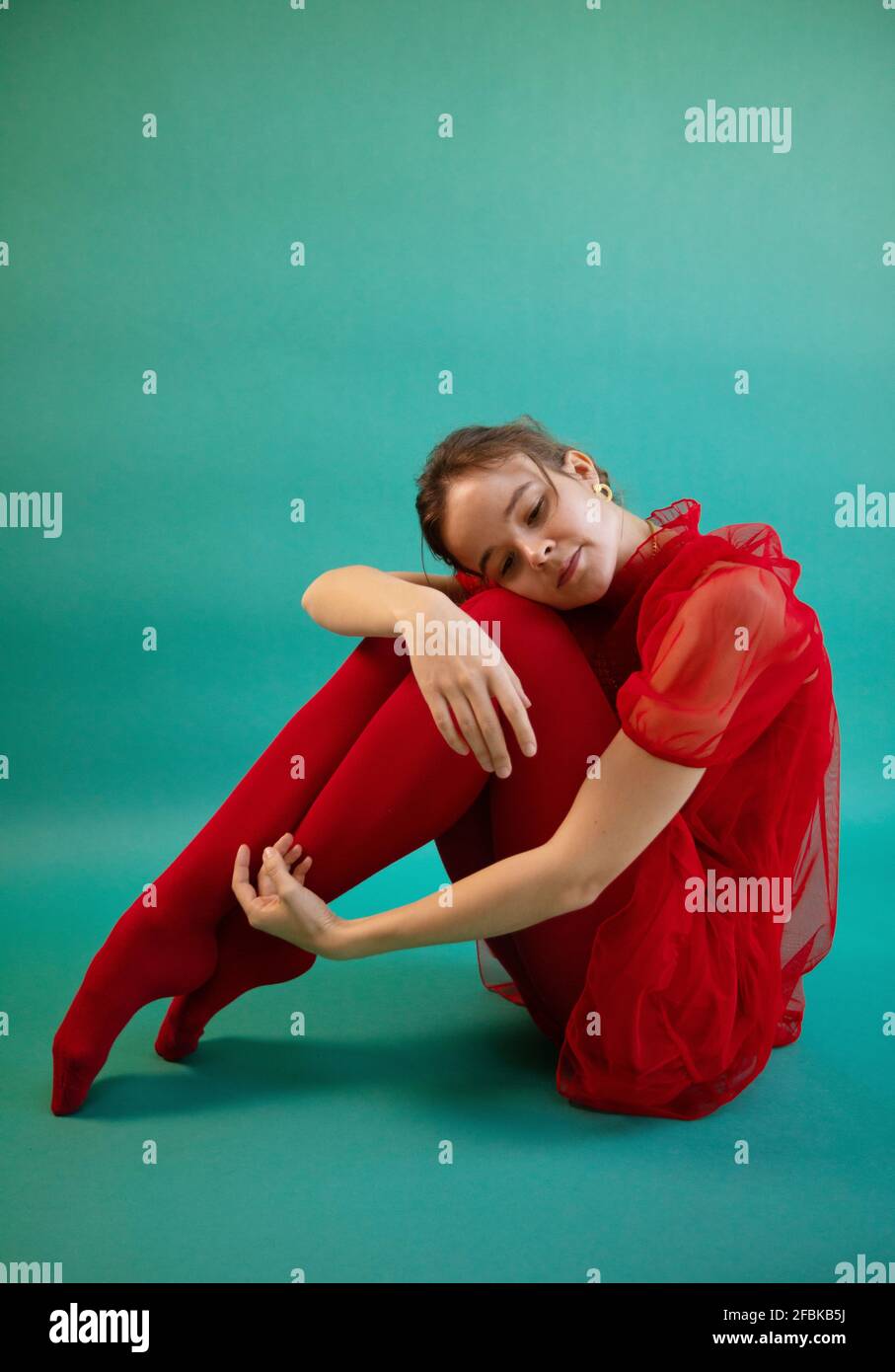 Young female dancer sitting on turquoise background Stock Photo - Alamy