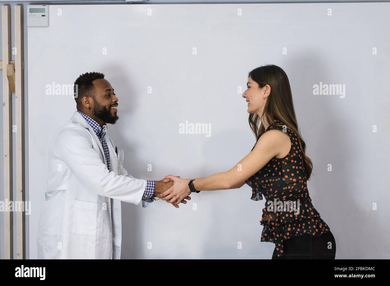 Smiling male medical professional greeting female patient at clinic ...