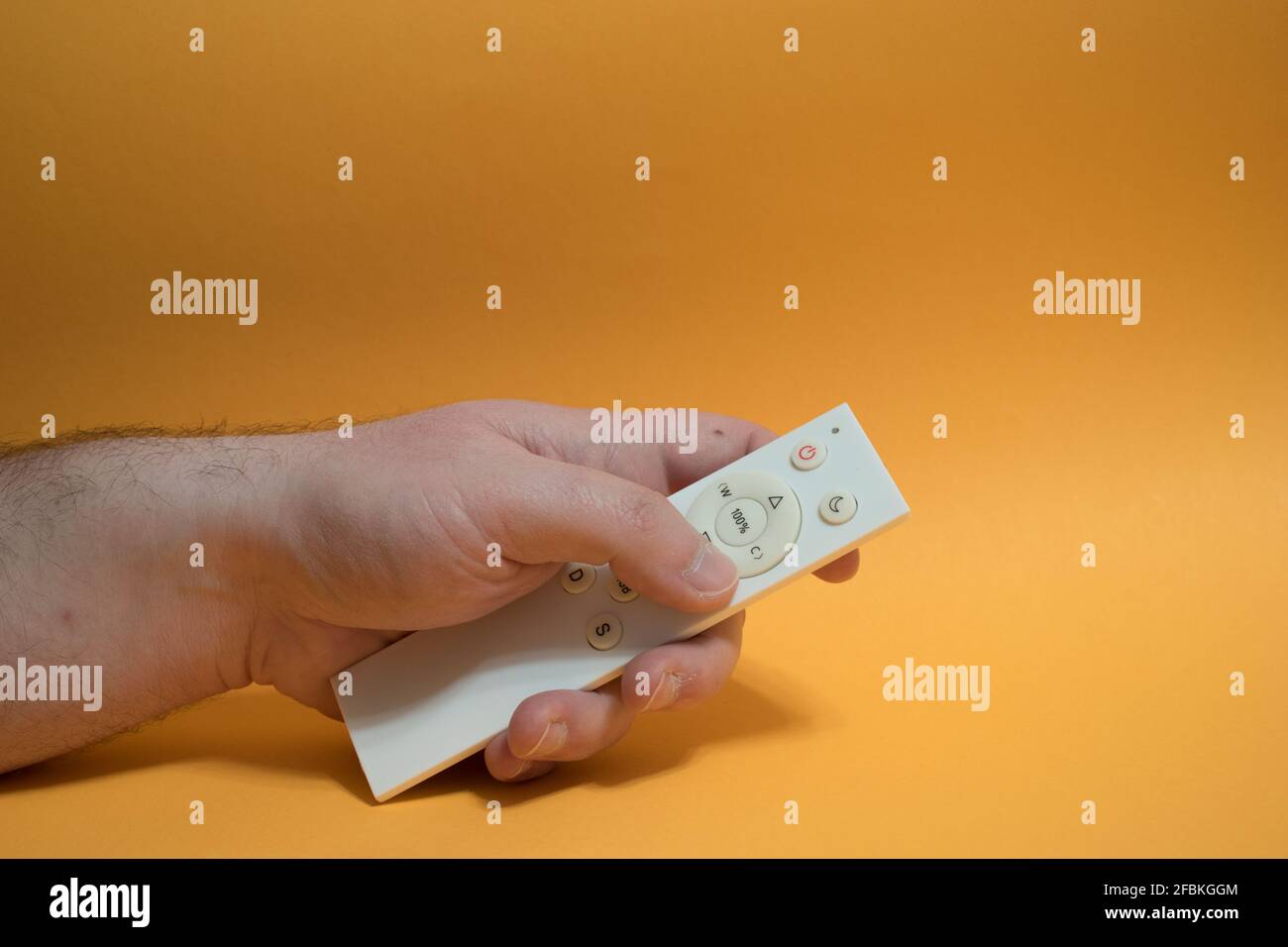 Human hand holding white remote control adjusting the electric light ...