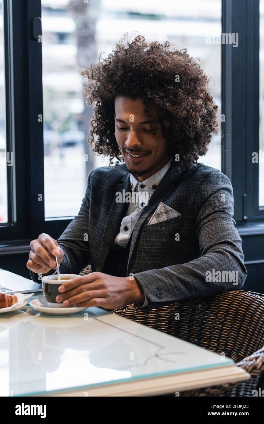 Mixed race businessman mixing coffee in cafe Stock Photo - Alamy