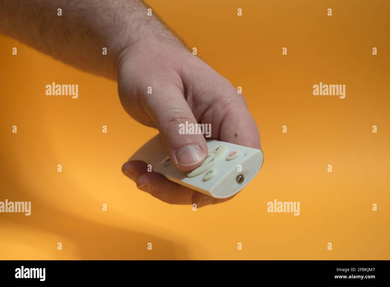 Human hand holding white remote control adjusting the electric light ...