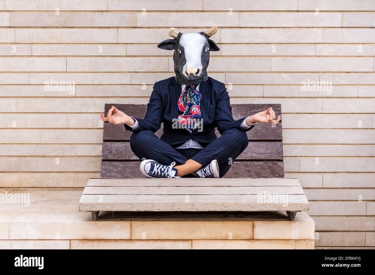 Businesswoman wearing bull mask practicing lotus position sitting on ...