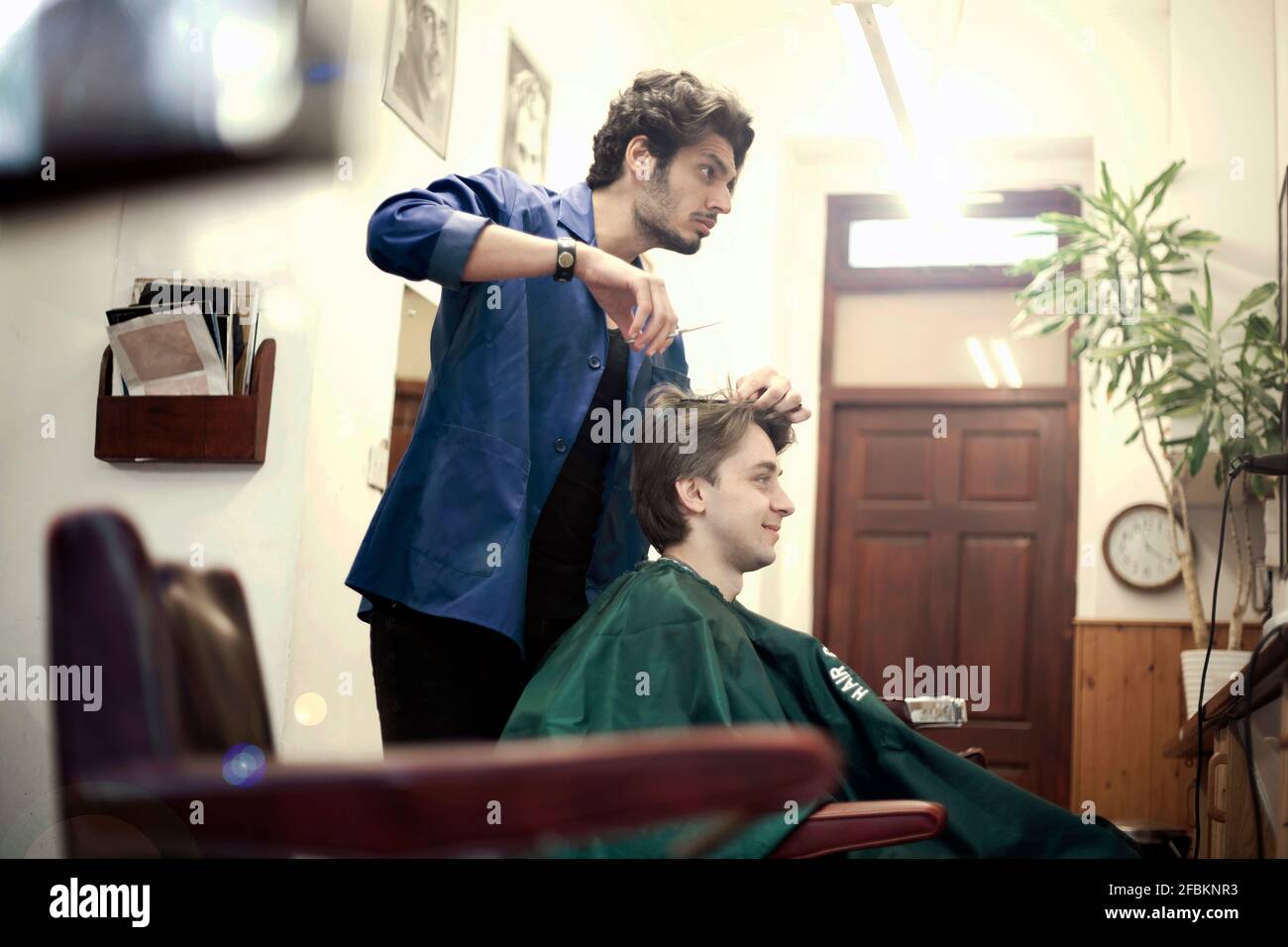 Barber cutting hair of male customer Stock Photo - Alamy