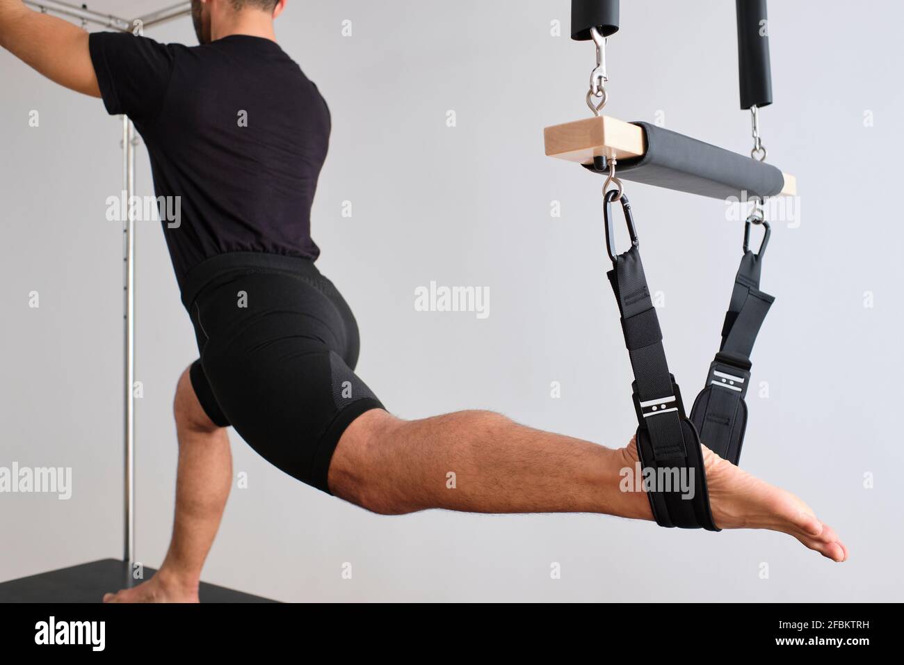 Man stretching leg while practicing pilates on trapeze table in ...
