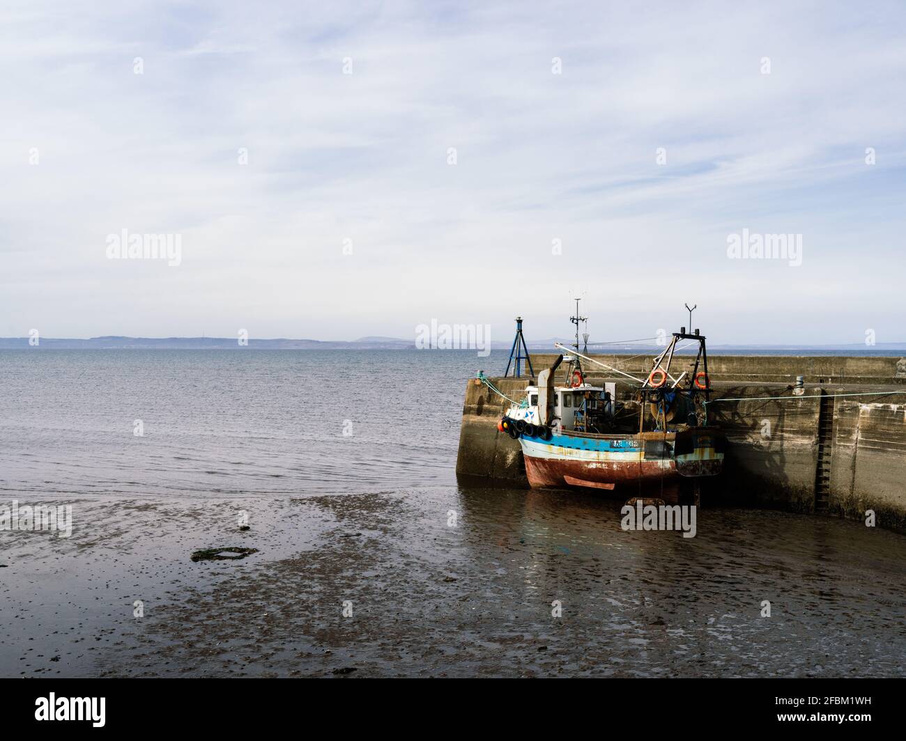 Prawn trawler tied up on the harbour entrance at low tide at Fisherrow ...
