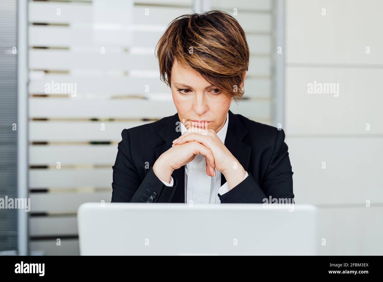 Contemplating female entrepreneur with brown hair sitting in front of ...