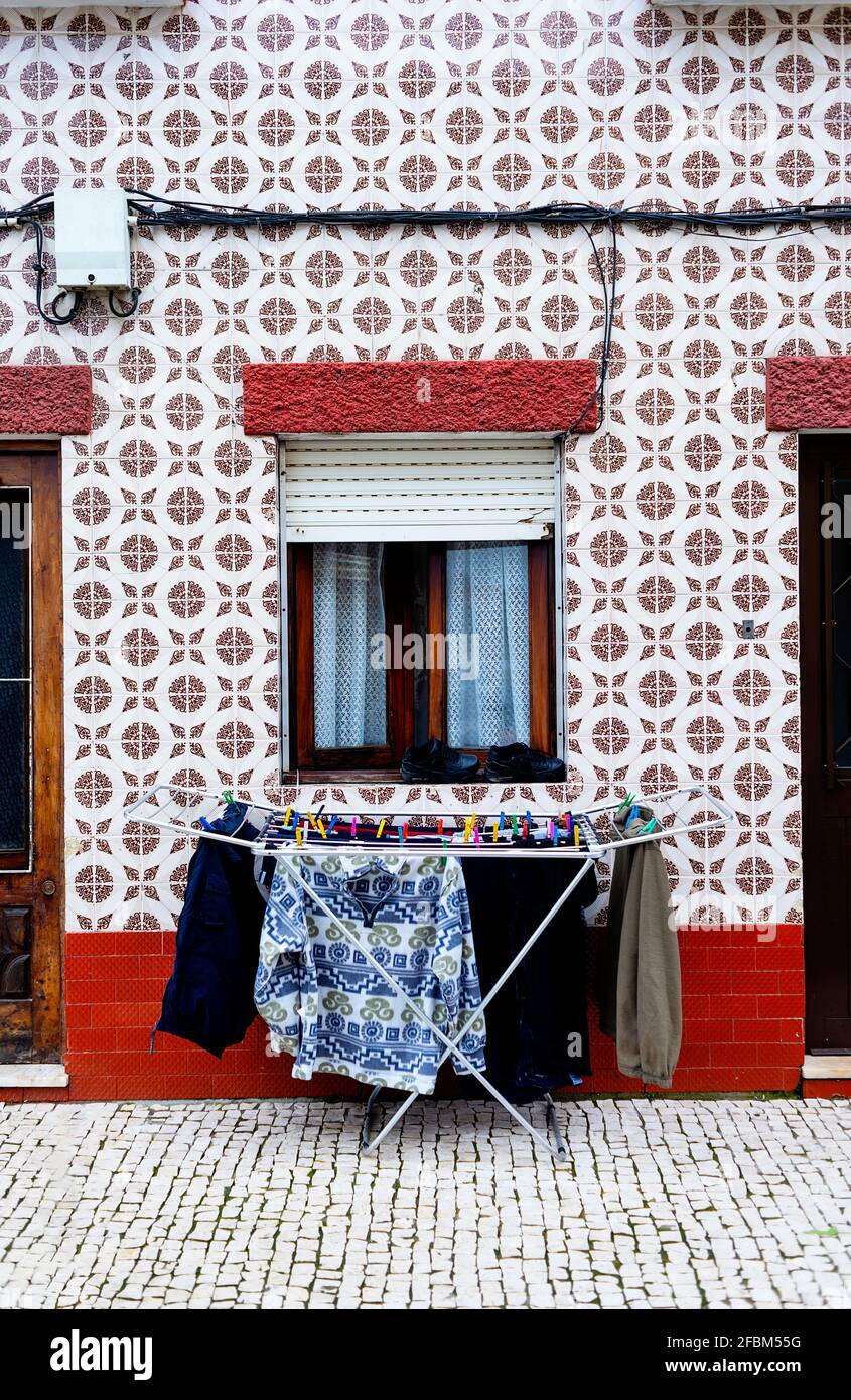 Laundry drying on drying rack standing in front of mosaic wall with ...