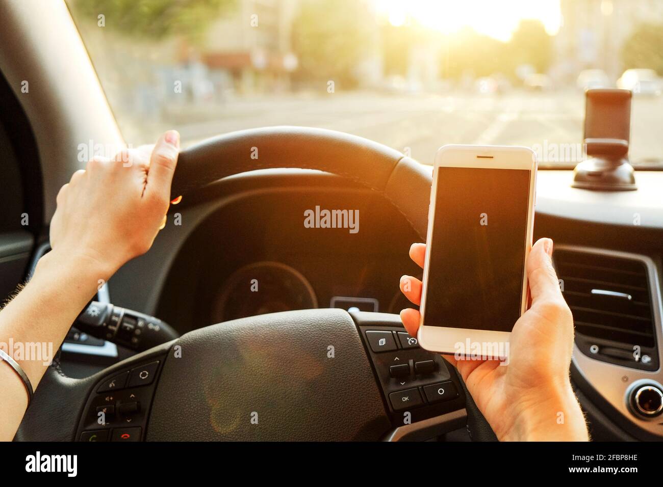 Young woman holding blank screen cell phone while driving car. Female ...