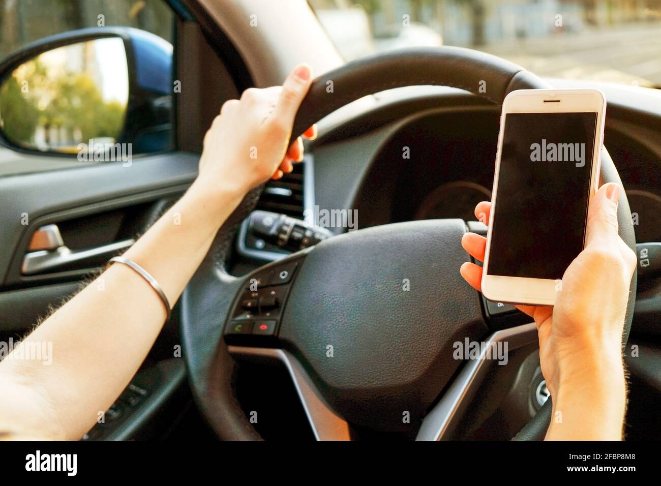 Young woman holding blank screen cell phone while driving car. Female ...