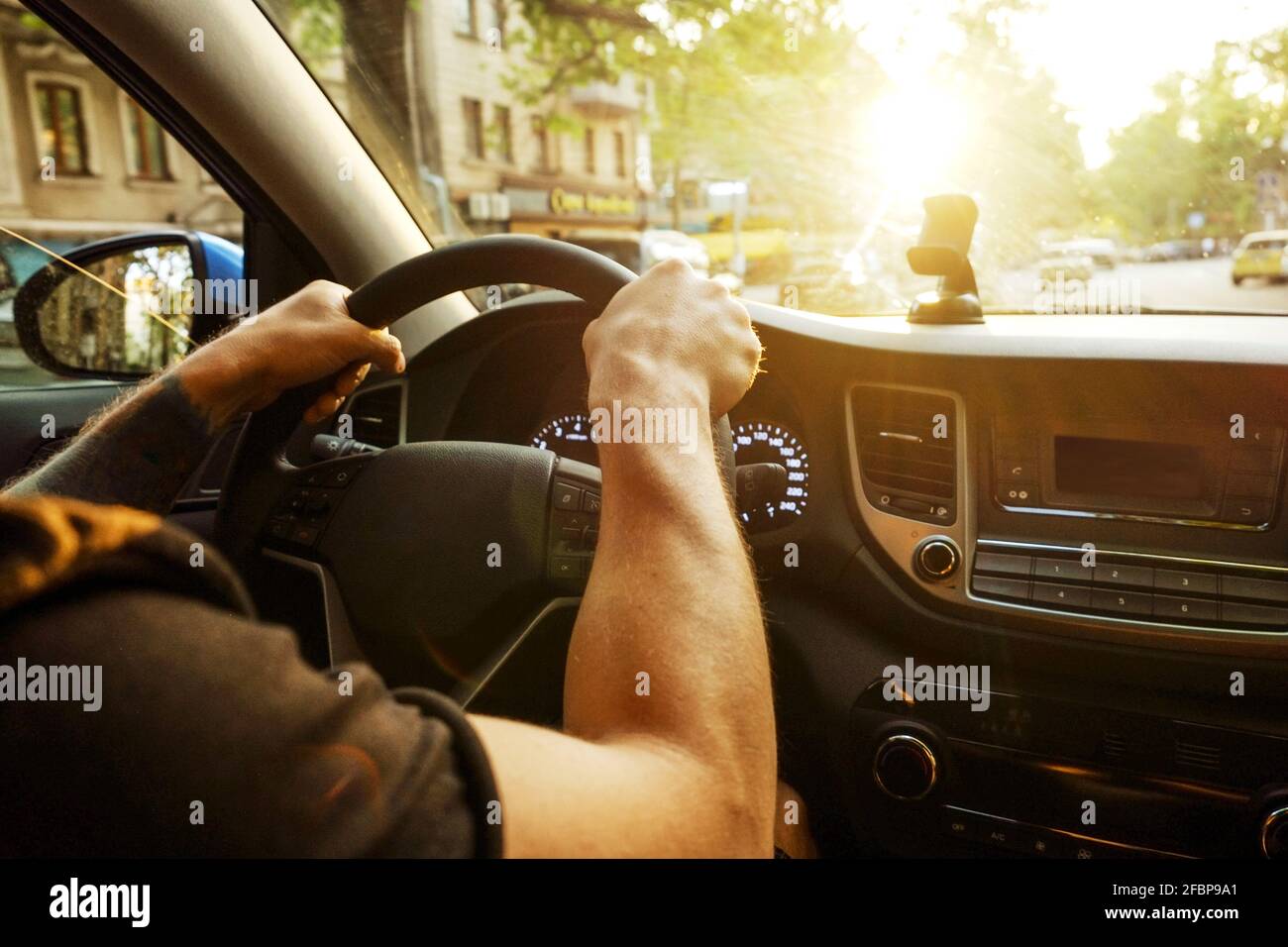 Young man in black t-shirt holding steering wheel, driving car, forearm ...