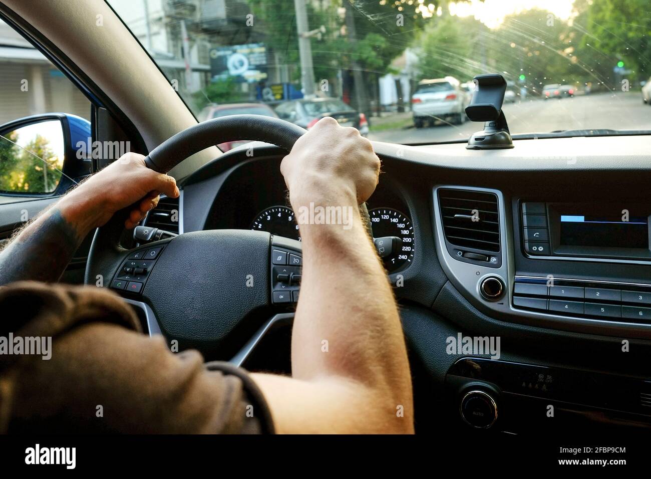 Young man in black t-shirt holding steering wheel, driving car, forearm ...