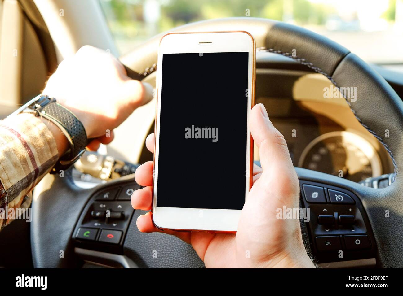 Young man holding blank screen cell phone while driving car. Male ...