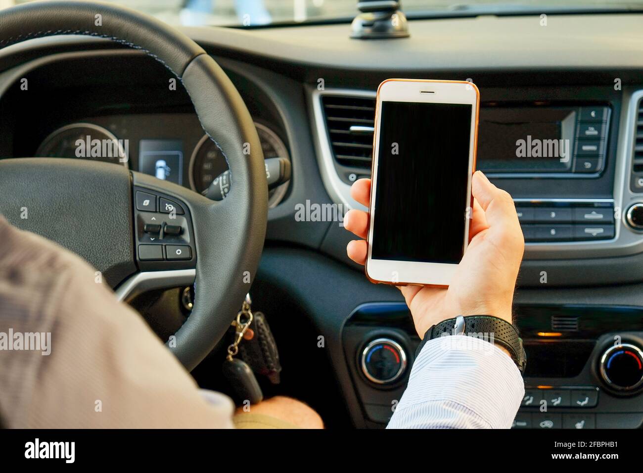 Young man holding blank screen cell phone while driving car. Male ...