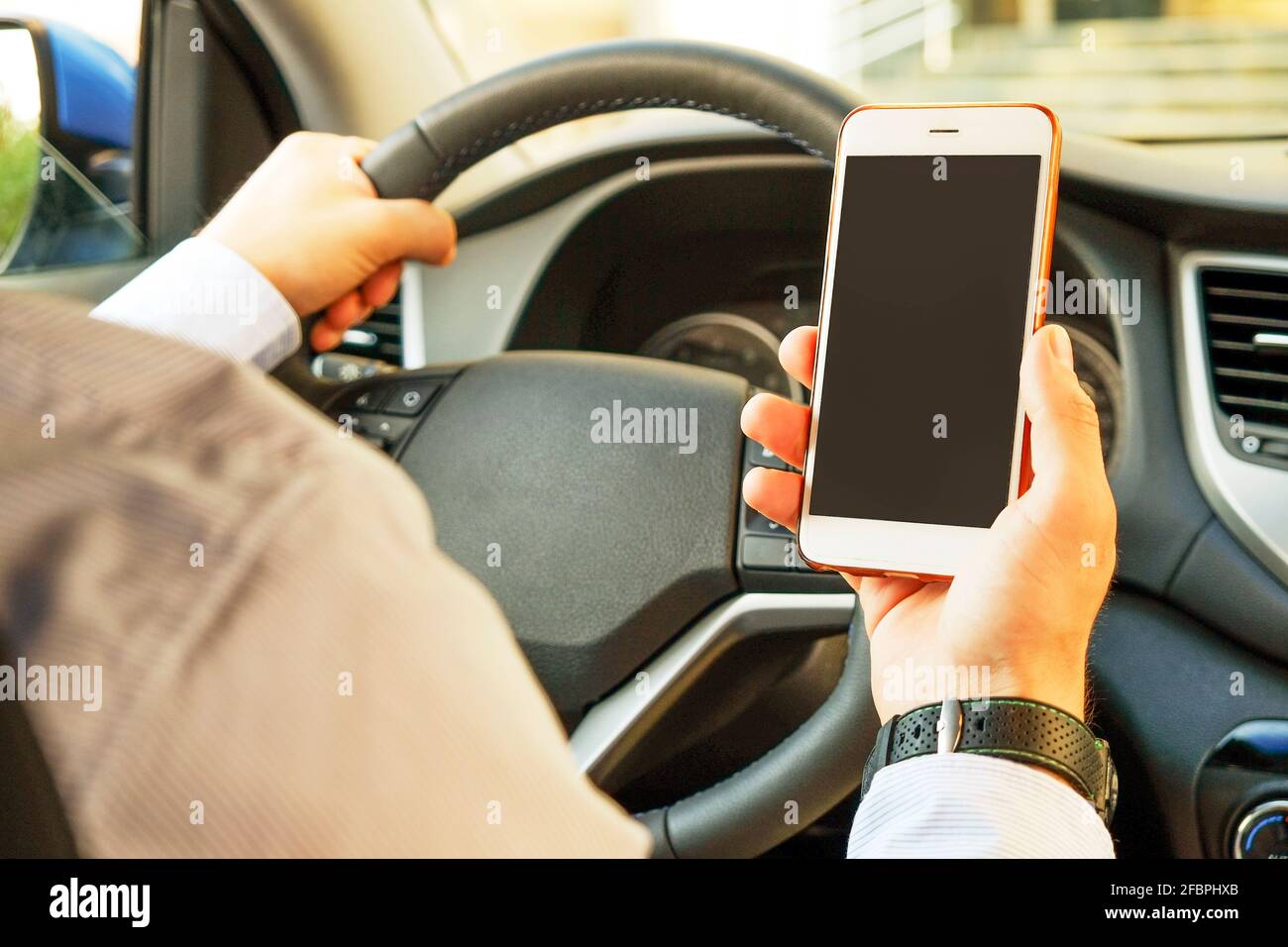 Young man holding blank screen cell phone while driving car. Male ...