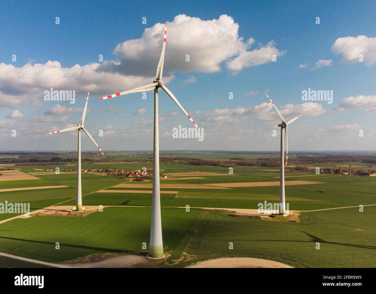 Aerial view of large wind turbines with blades in field against blue ...