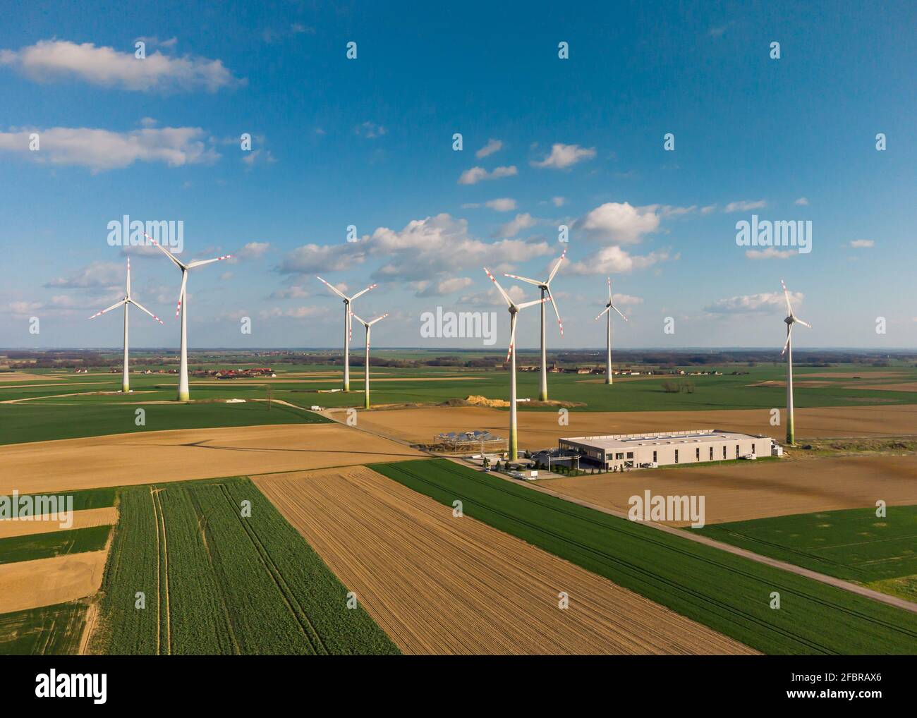 Aerial view of large wind turbines with blades in field against blue ...