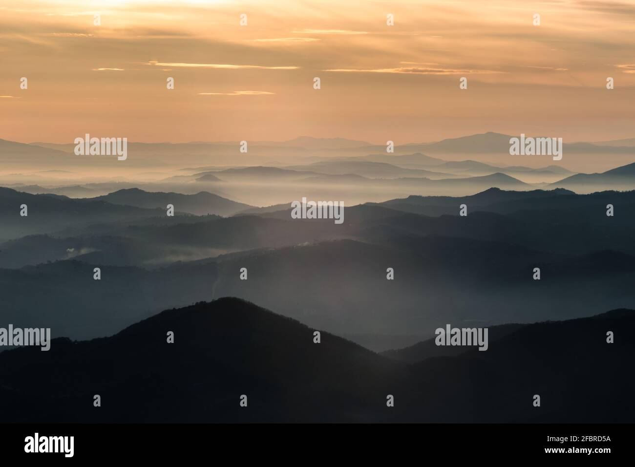 Mist and fog between valley and layers of mountains and hills at sunset ...