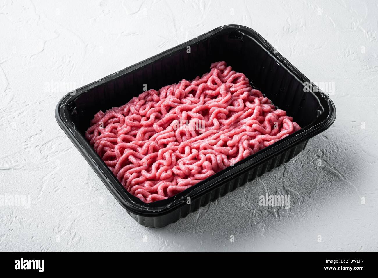 Fresh minced meat in plastic box packaging tray set, on white stone ...