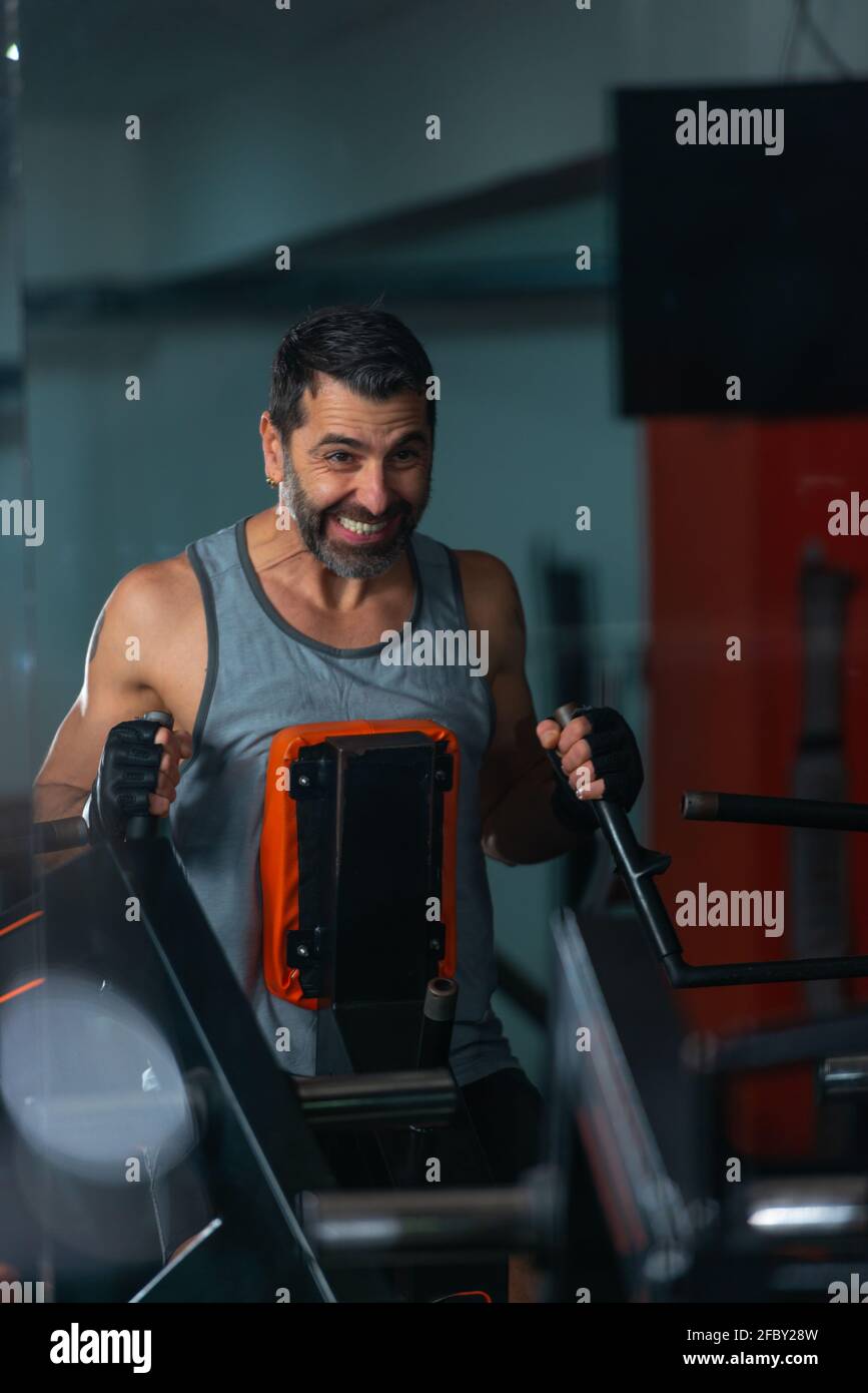 Front closeup view of 50 year old man using seated row machine in ...