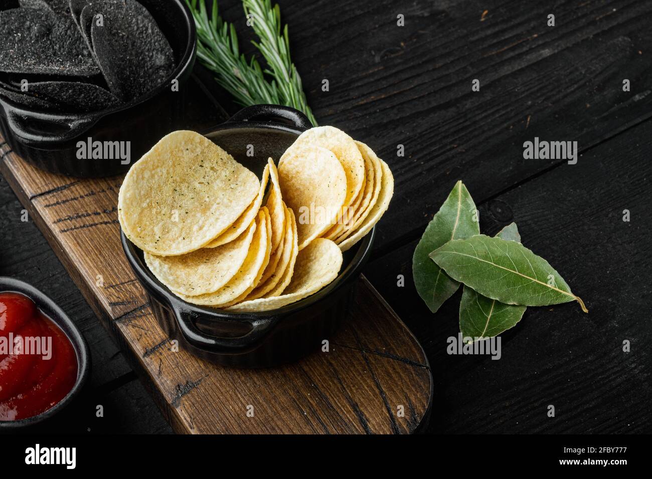 Salty potato chips snack set, on black wooden background Stock Photo ...