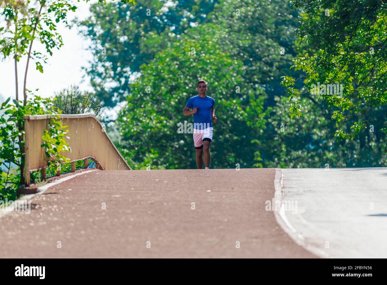 Athletic young man running on the race track in a sports park Stock ...