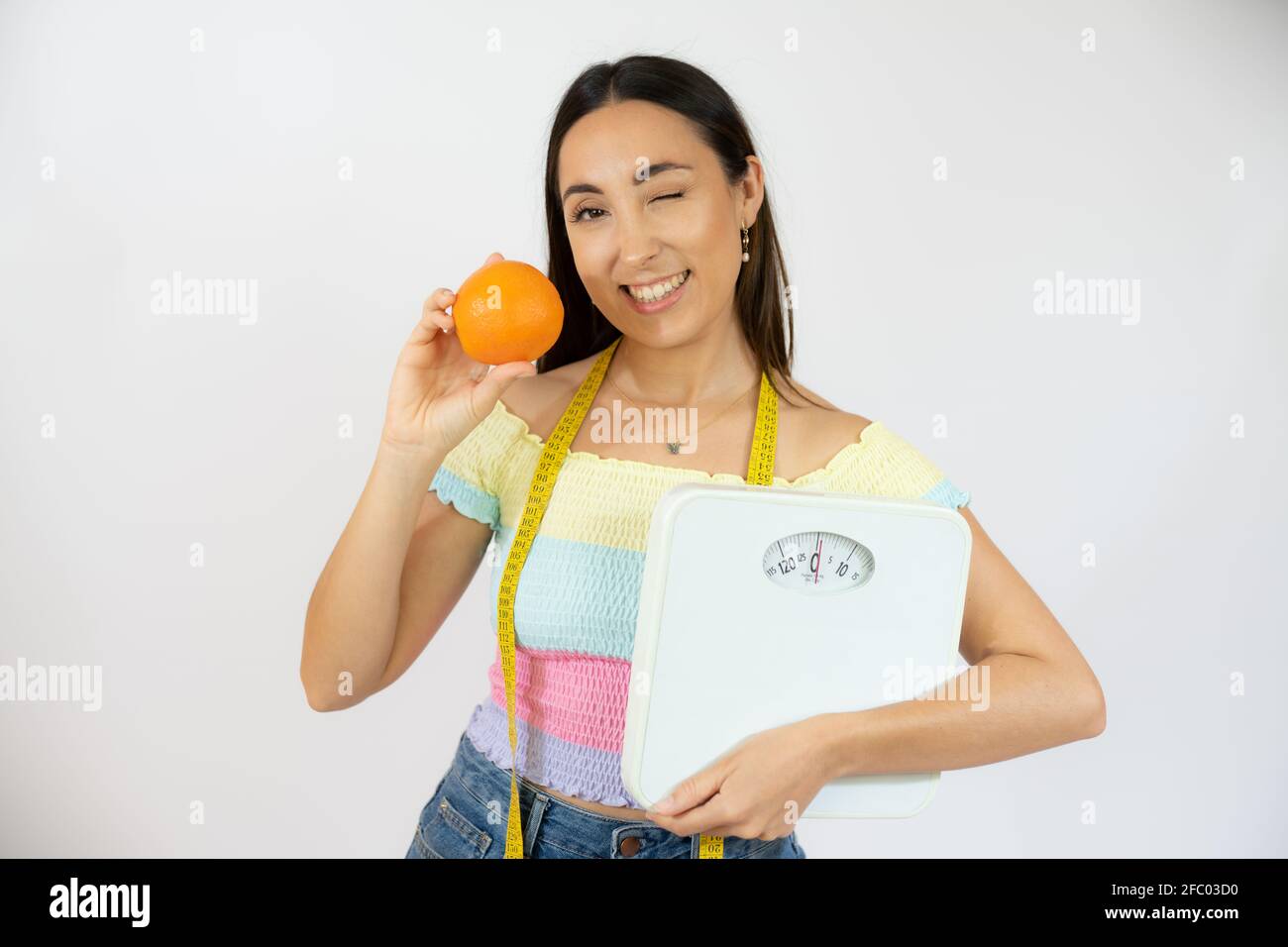 Portrait of a funny young woman holding a scale and an orange Stock ...