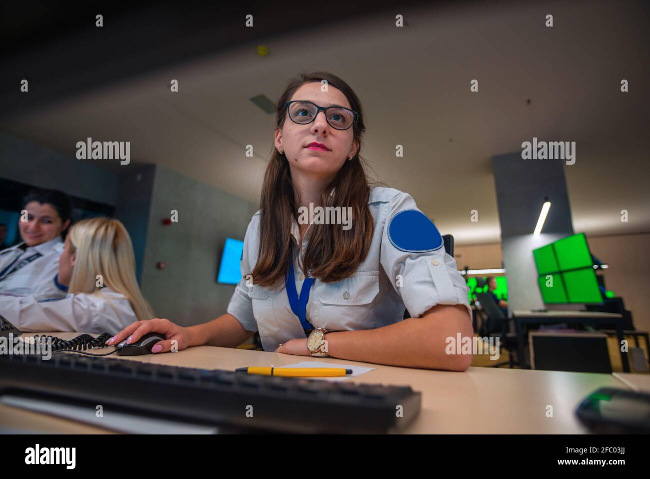 Female security guards working on computers while sitting in the main ...