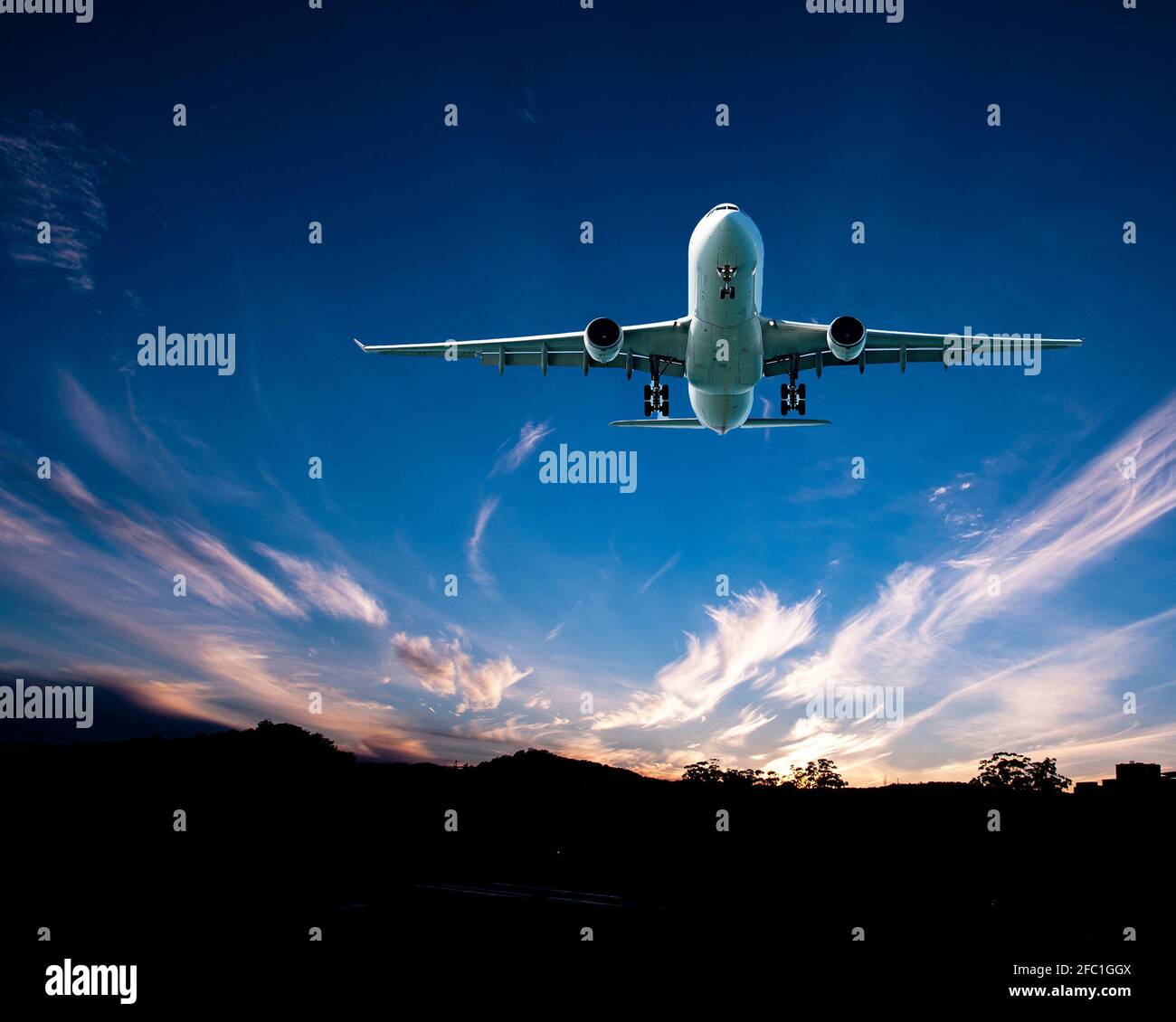 A passenger jet airliner flying overhead closeup in a cobalt blue sky ...