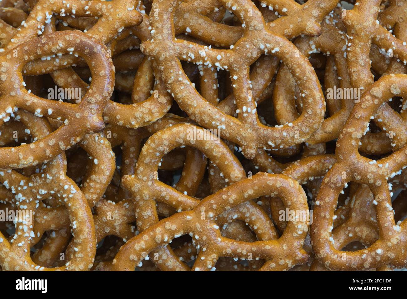 Many salted pretzels scattered loosely, close up directly above. Savory ...