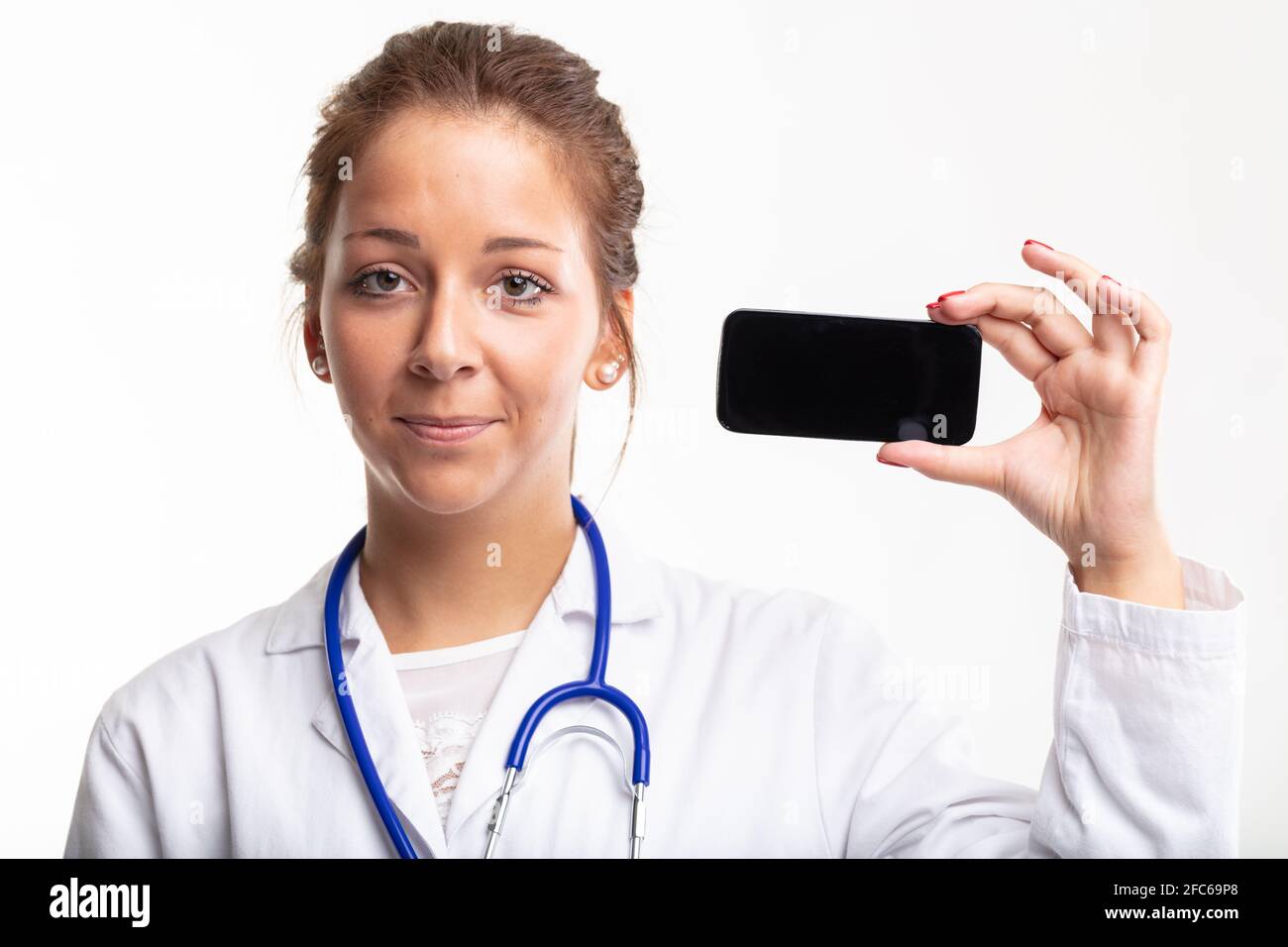 Young female doctor or nurse holding up a blank mobile phone with the ...